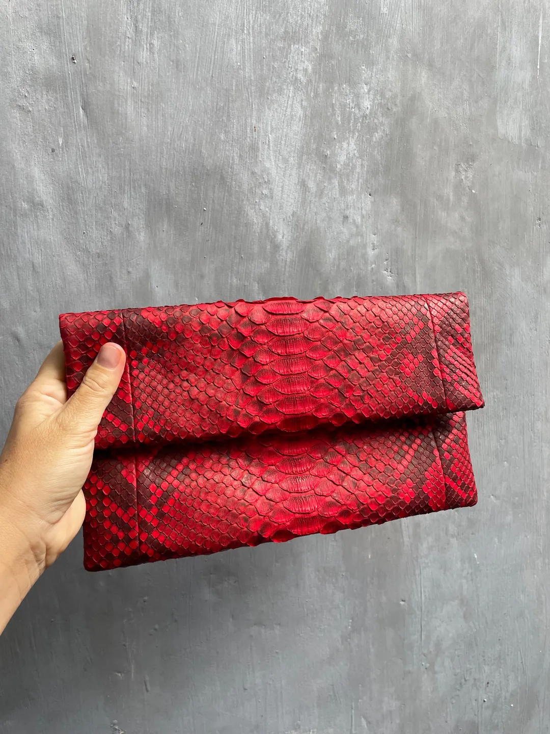 Red clutch from genuine leather with patterns on the chain