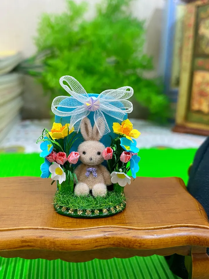 Easter miniature. Bunny on a stand with flowers.